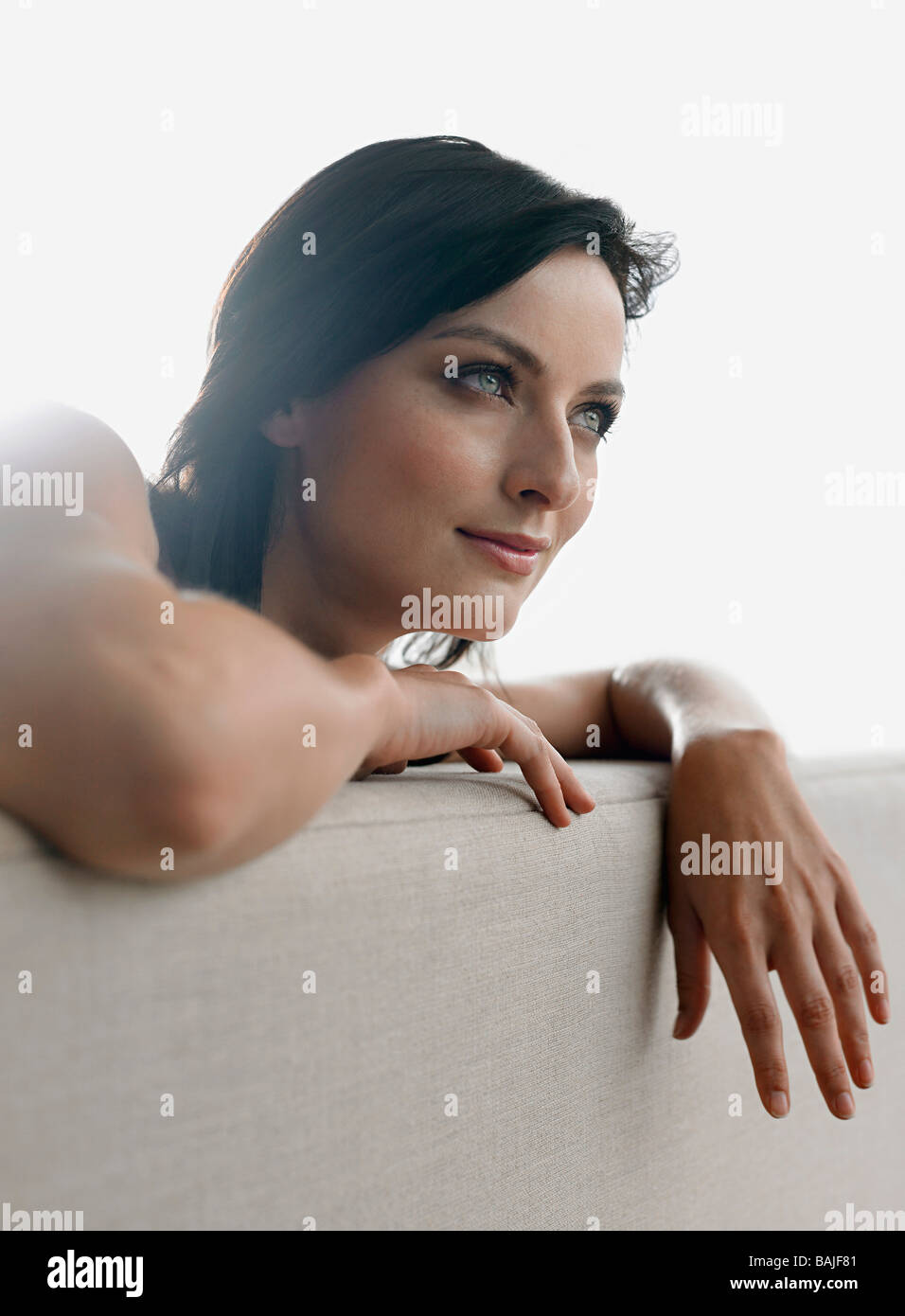 Young woman leaning on couch indoors Stock Photo - Alamy