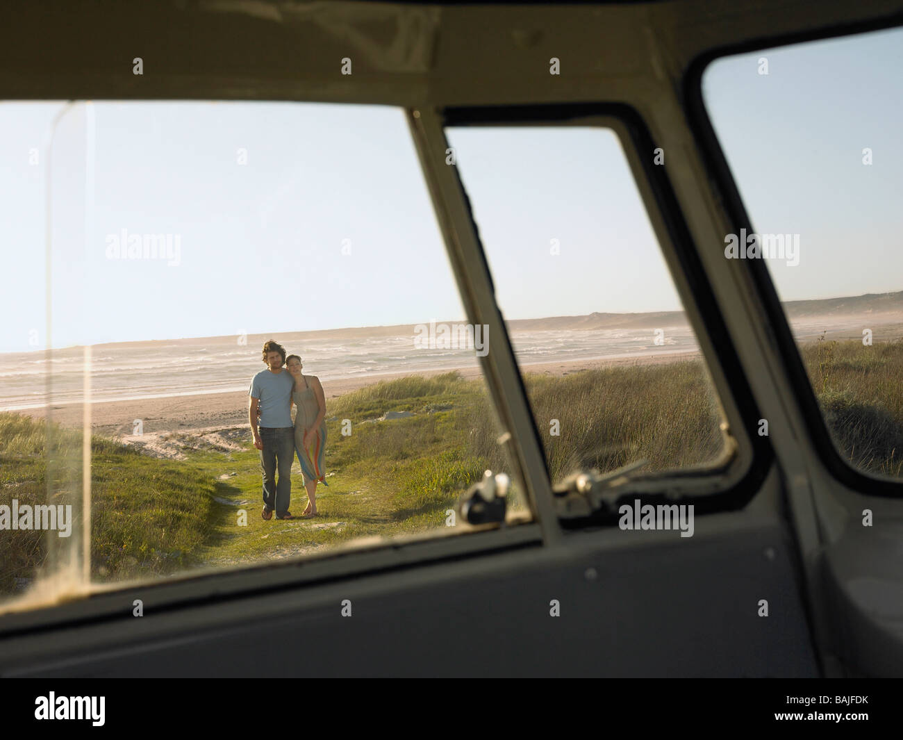 Couple walking towards camper van from beach, view through camper van ...