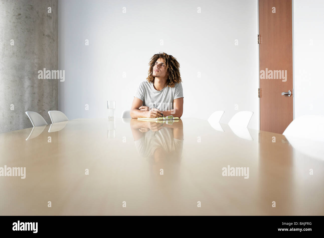 Young man sitting at conference table Stock Photo - Alamy