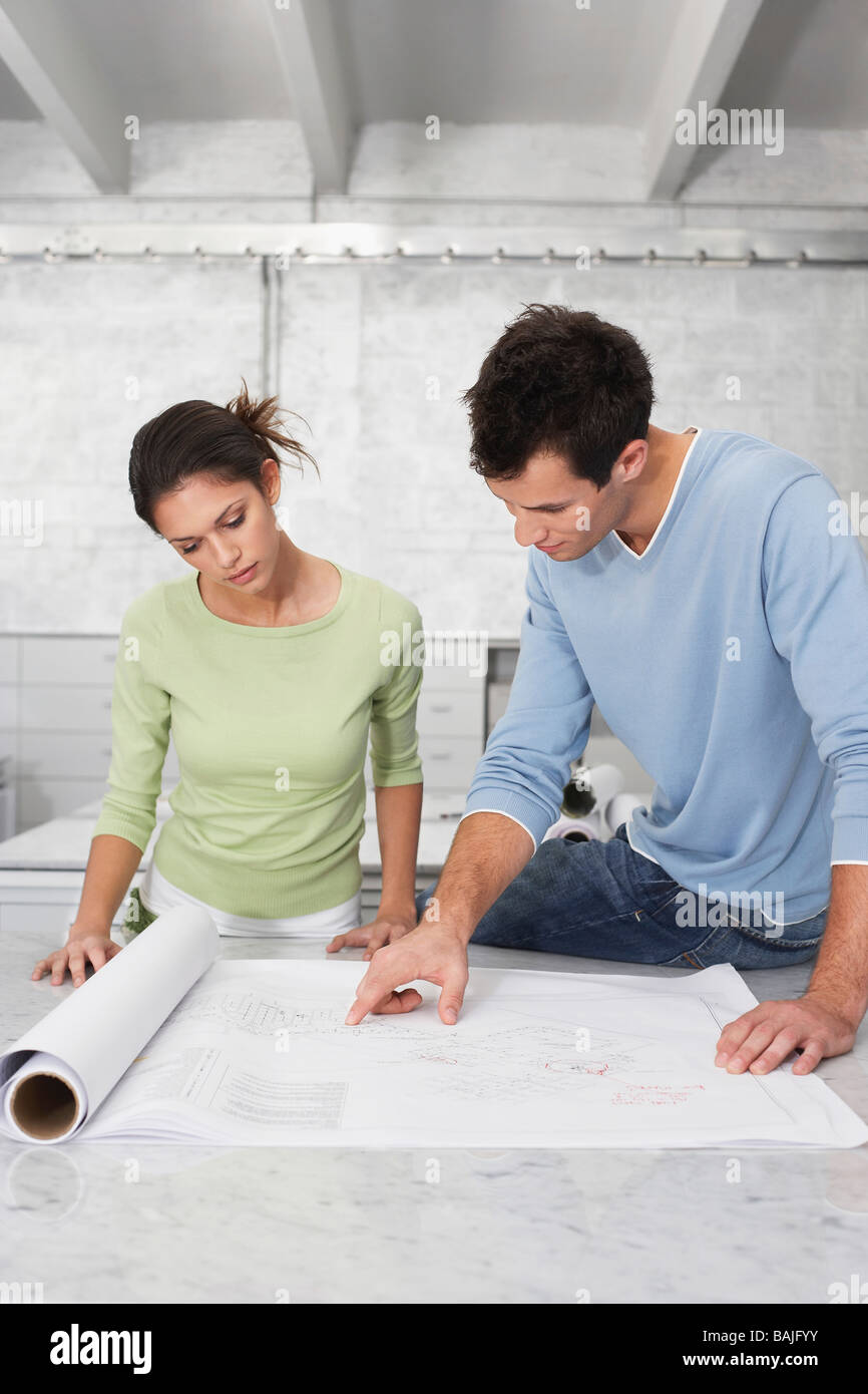 Young couple at desk, man pointing at blueprint Stock Photo - Alamy