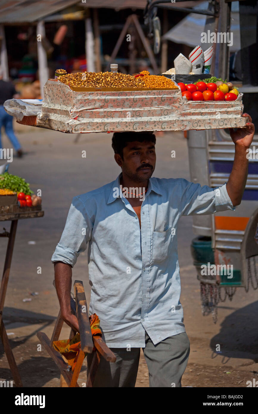 Man carrying food on a tray on head selling at bus stop for tourists in ...