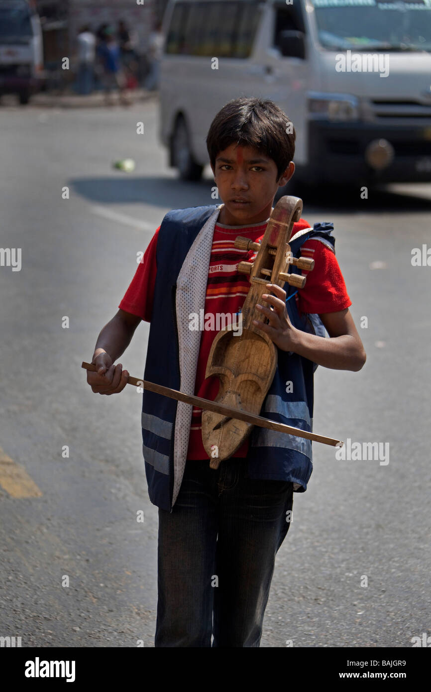 Young boy playing violin musical instrument in street for tourist ...