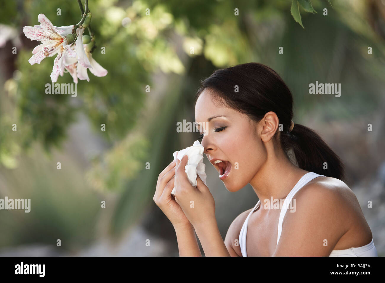Woman sneezing under tree Stock Photo - Alamy