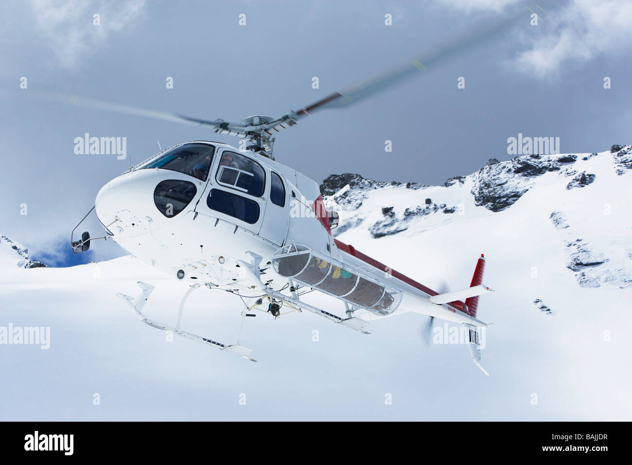Helicopter flying over snowy mountain peaks Stock Photo - Alamy
