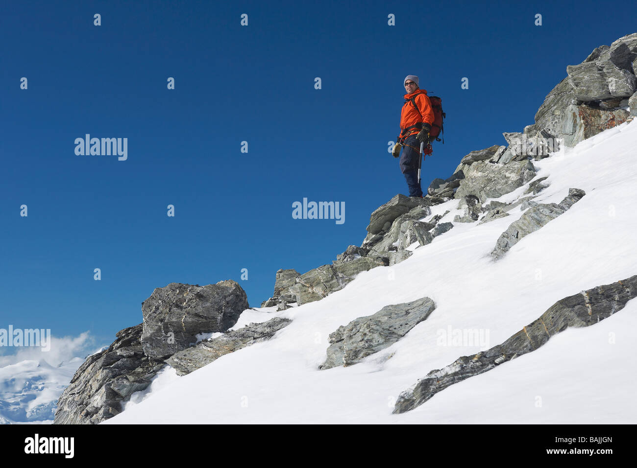 Mountain climber descending snow and boulder slope Stock Photo - Alamy