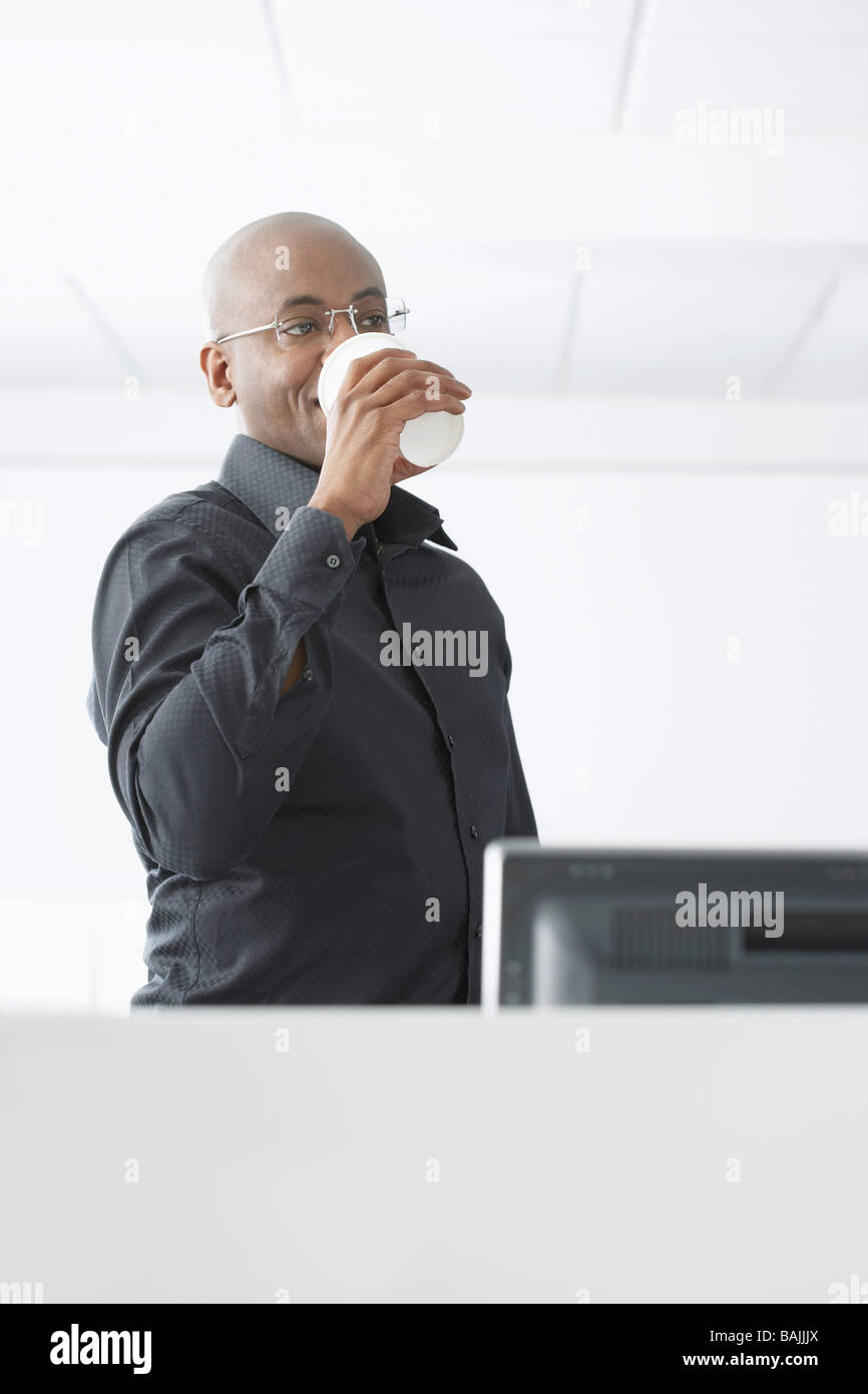 Office worker drinking coffee in office Stock Photo - Alamy