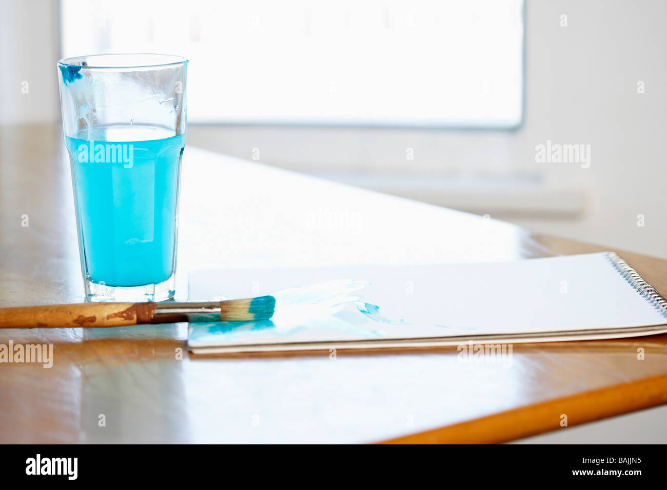 Paintbrush and pad by glass of blue water Stock Photo - Alamy
