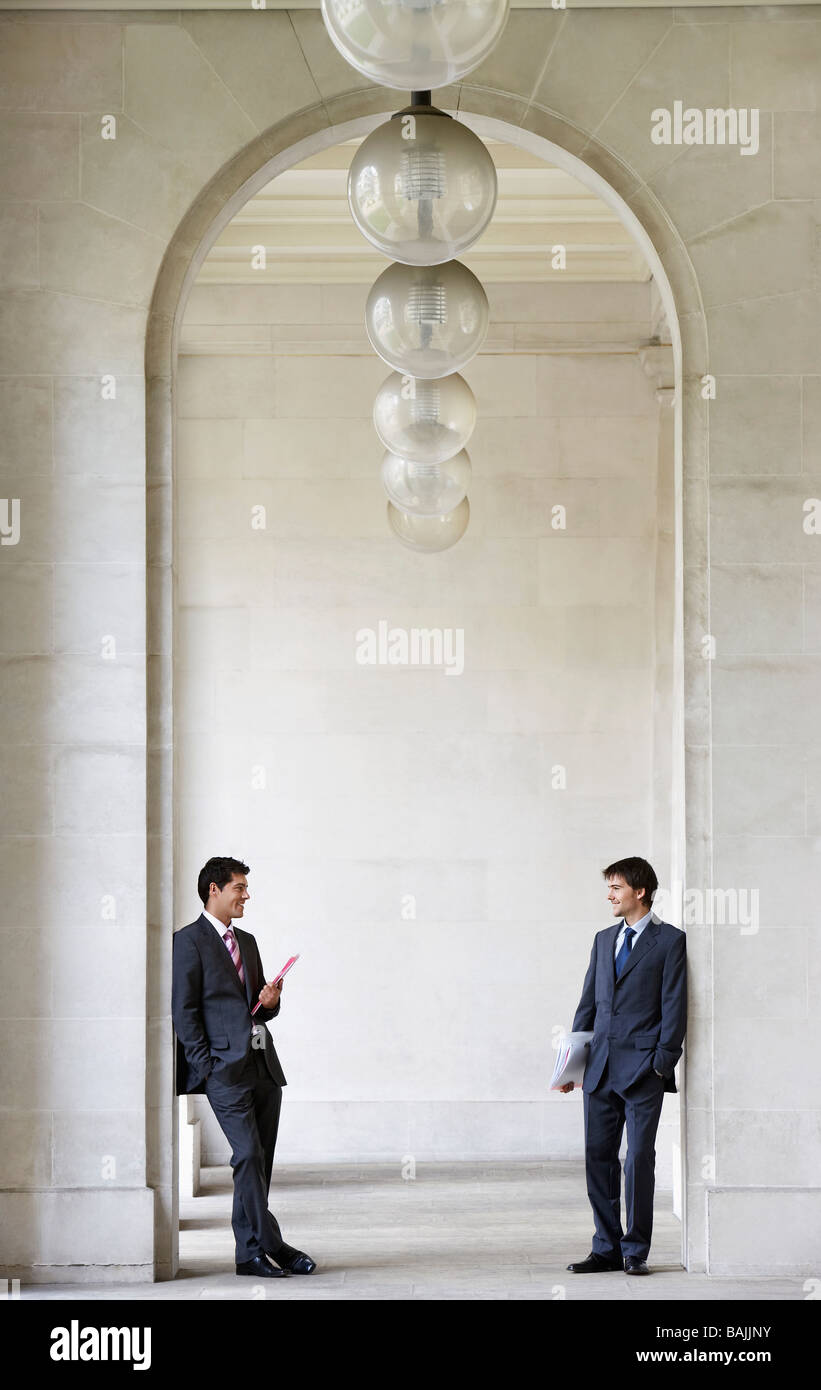 Two Businessmen outside building in archway talking Stock Photo - Alamy