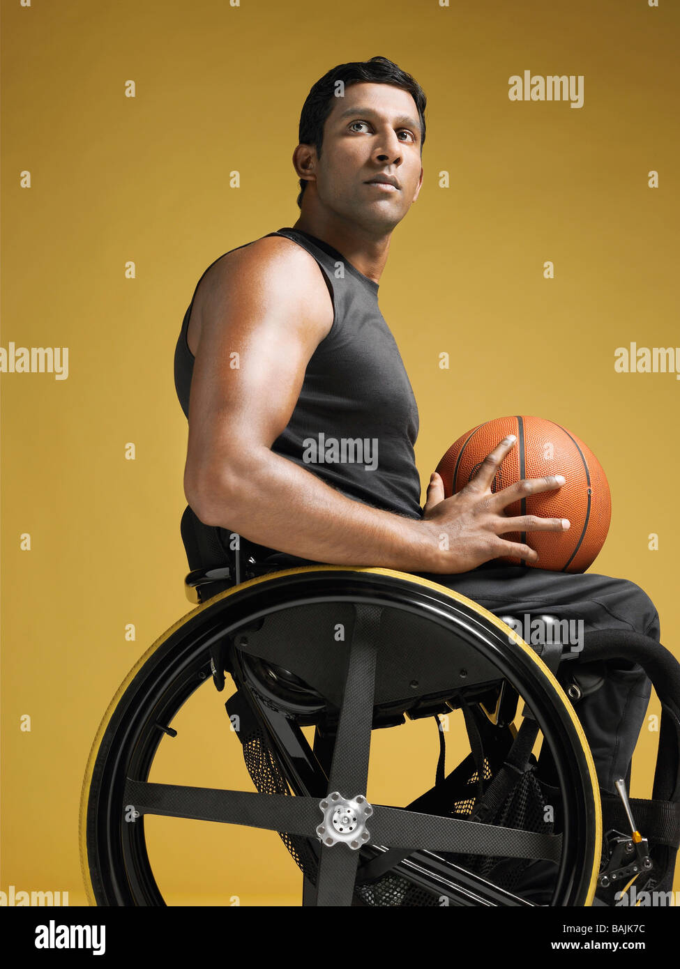 Paraplegic athlete sitting in wheelchair holding basketball, side view ...