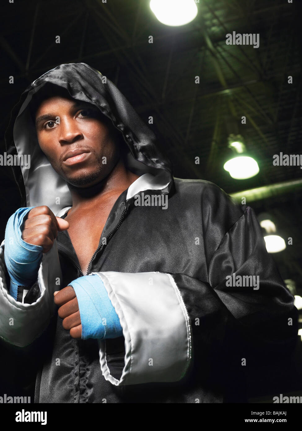 Boxer wearing robe with hood up, clenching fists, portrait Stock Photo ...