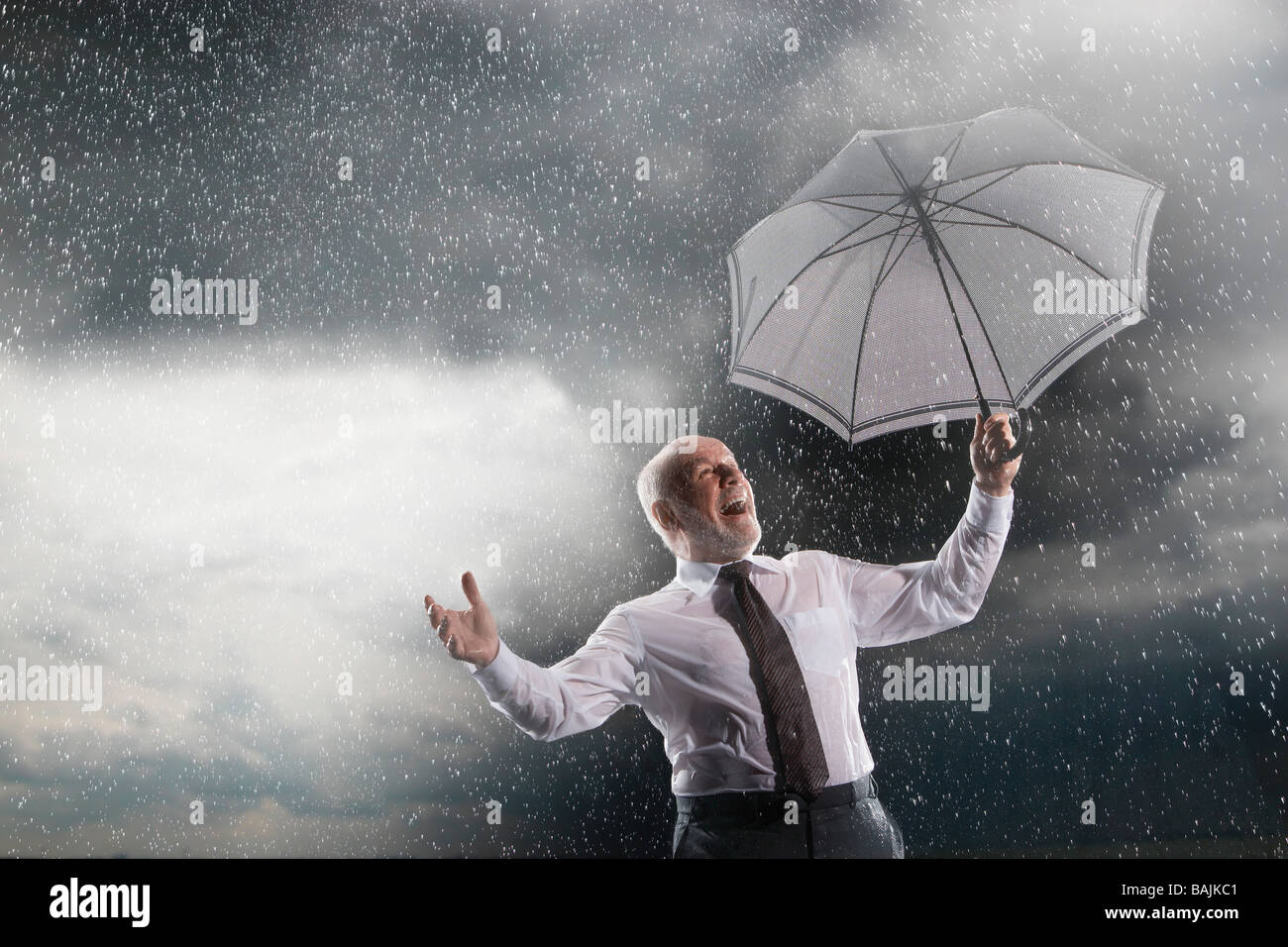 Businessman holding umbrella, Laughing in Storm, low angle view Stock ...