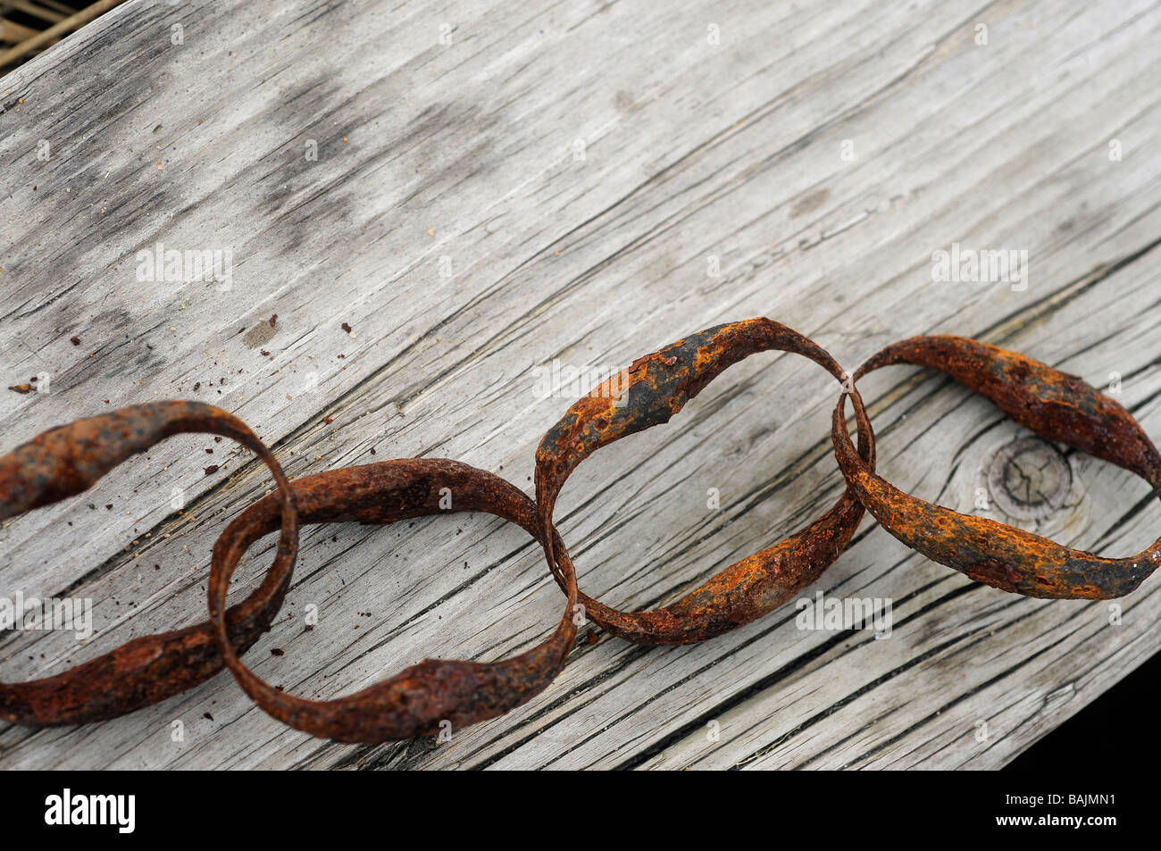 Rusted chain links laying on weathered dock board after being pulled ...
