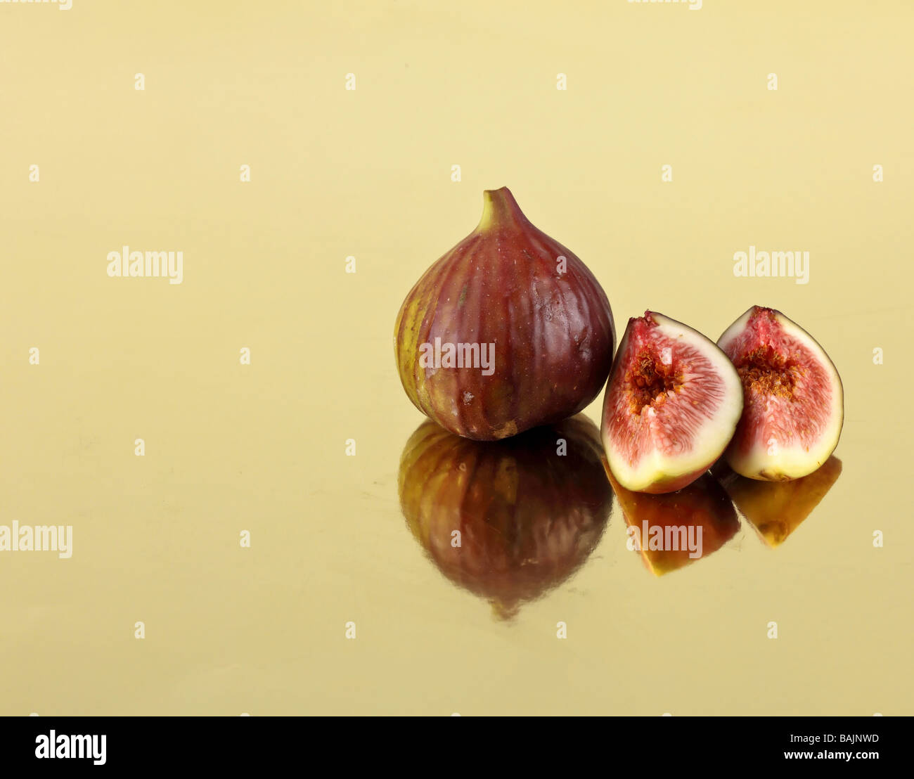 Figs arranged on a golden background with one fig sliced into segments ...