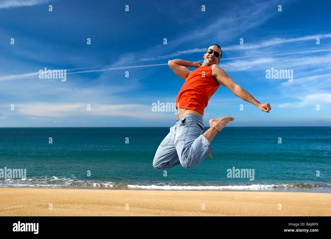 Man jumping on a the beach with a beautiful cloudy sky Stock Photo - Alamy