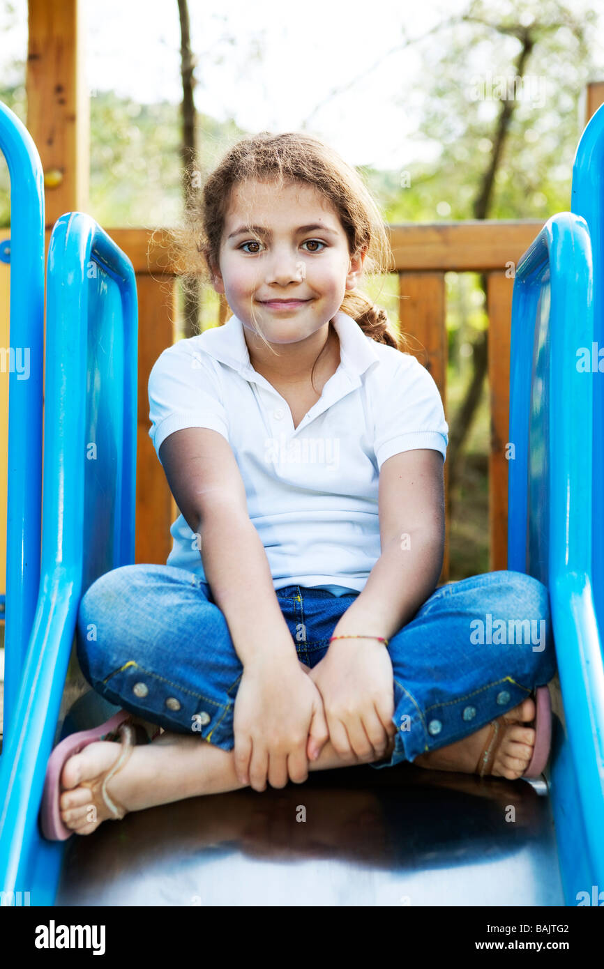 Child sitting on a slide with crossed legs Stock Photo - Alamy