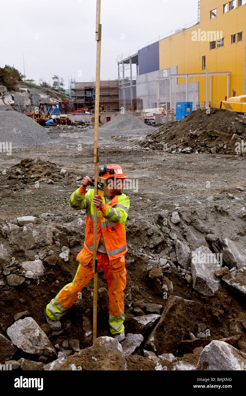 Construction worker marks out an area on a building site to be measured ...