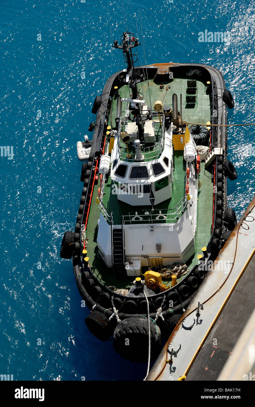 A tugboat pulls alongside a cruise ship in port Stock Photo - Alamy