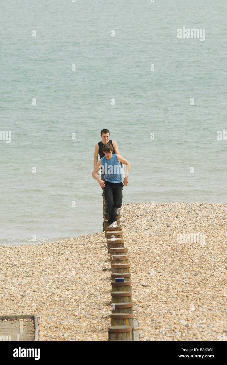 Boys balancing on beach groyne Stock Photo - Alamy