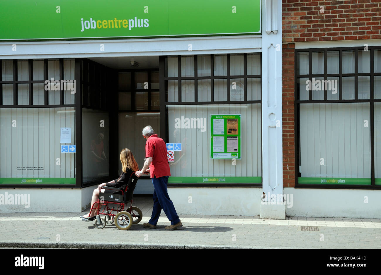Job centre disabled woman in wheelchair visiting with her male carer ...