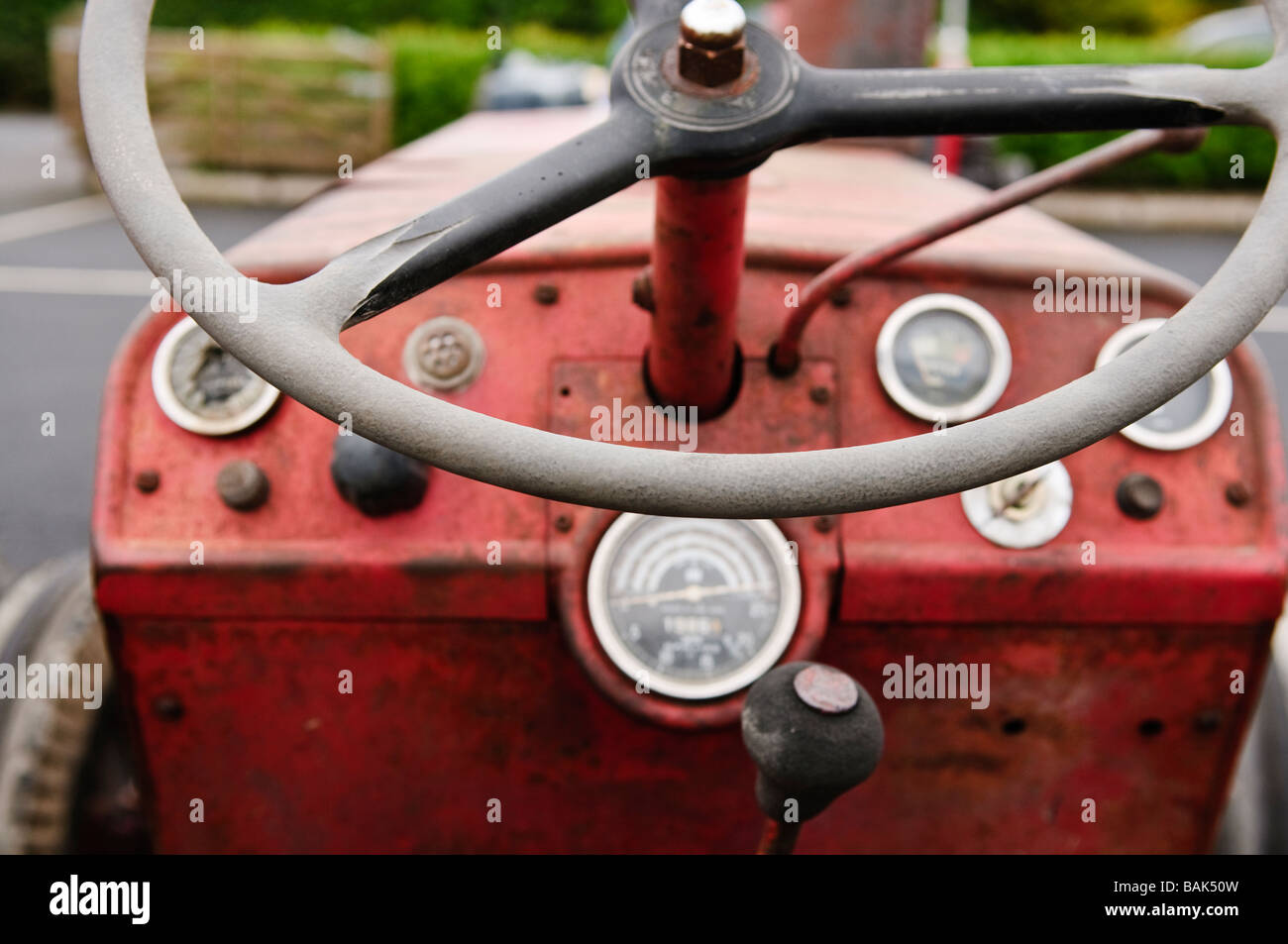 Rusty instrument panel of a red vintage farm tractor showing steering ...