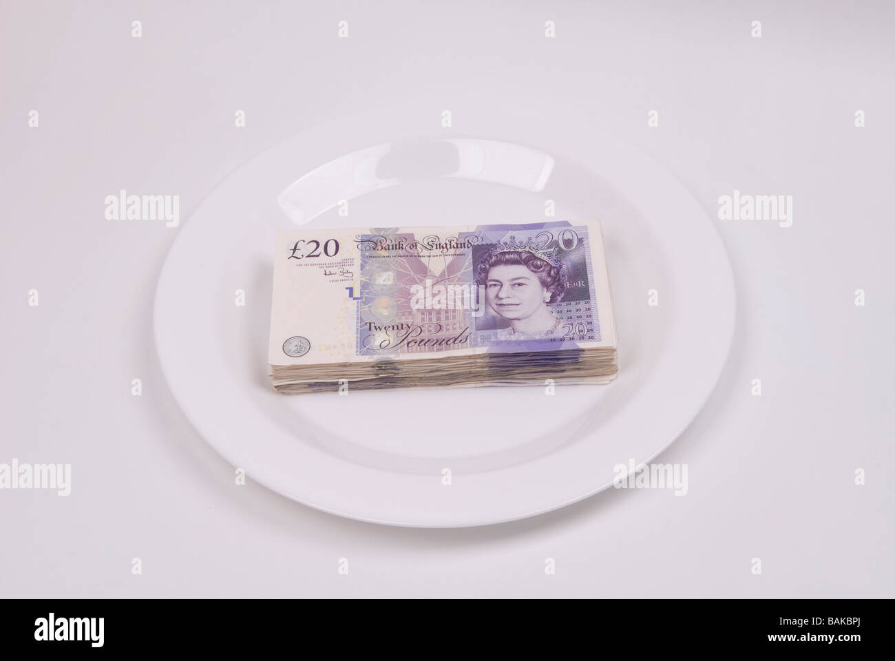 Stack of British money on a white plate Stock Photo - Alamy