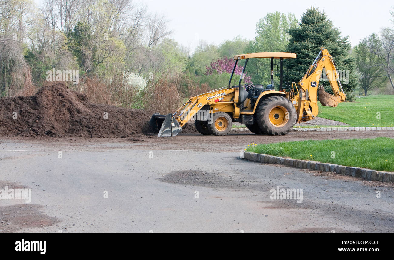 A yellow John Deere tractor with a pile of mulch. Front loader backhoe ...