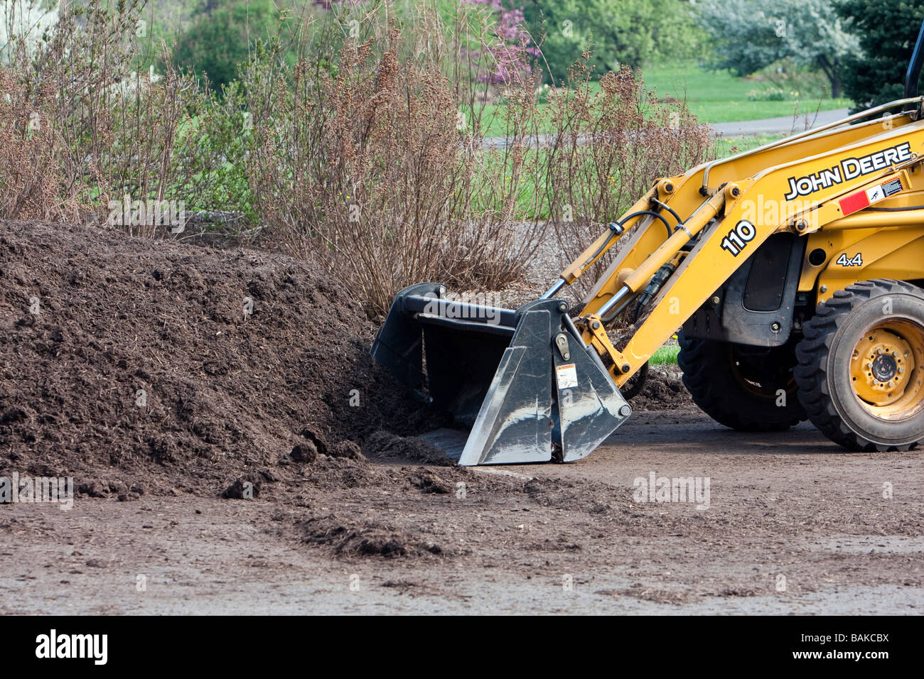 A yellow John Deere tractor with a pile of mulch. Front loader backhoe ...