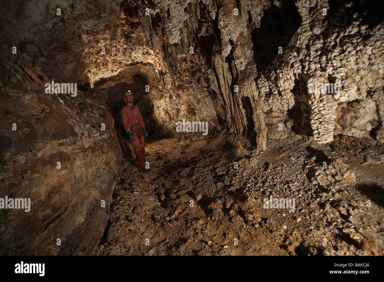 A Russian cave explorers stands and admires the fine cave formations ...