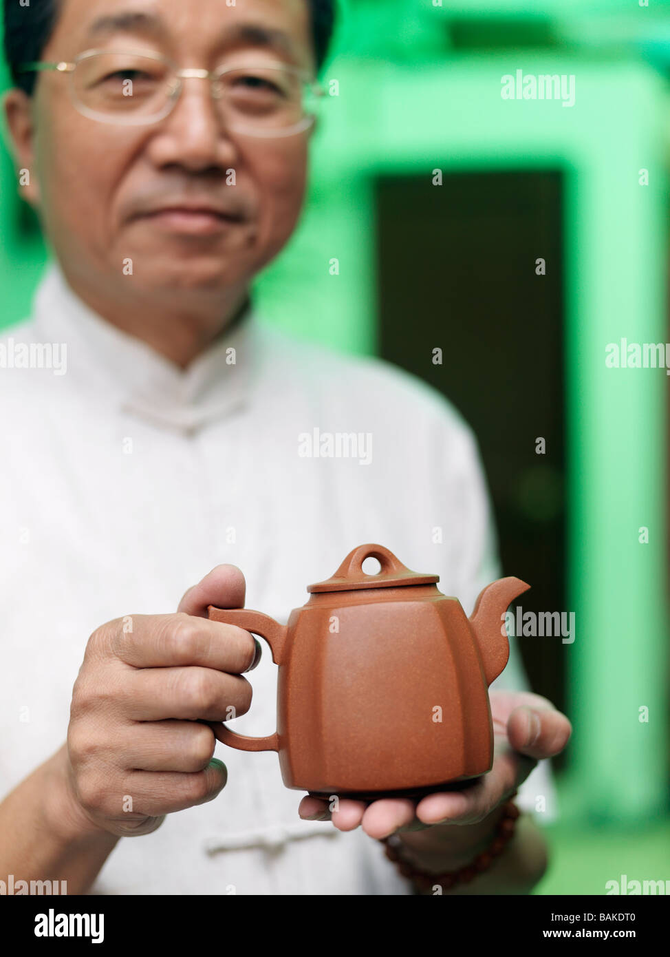 A Chinese man displaying a small terracotta colored tea pot Stock Photo ...