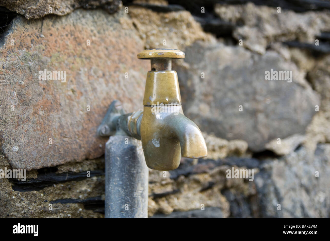 an old rustic brass push top tap fixed to a stone wall Stock Photo - Alamy