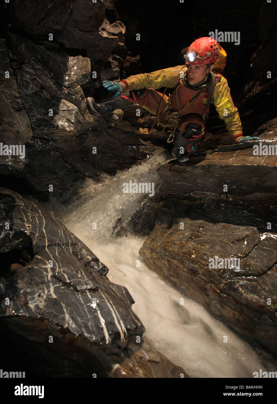 A cave explorer traversing a fast flowing stream passage deep ...