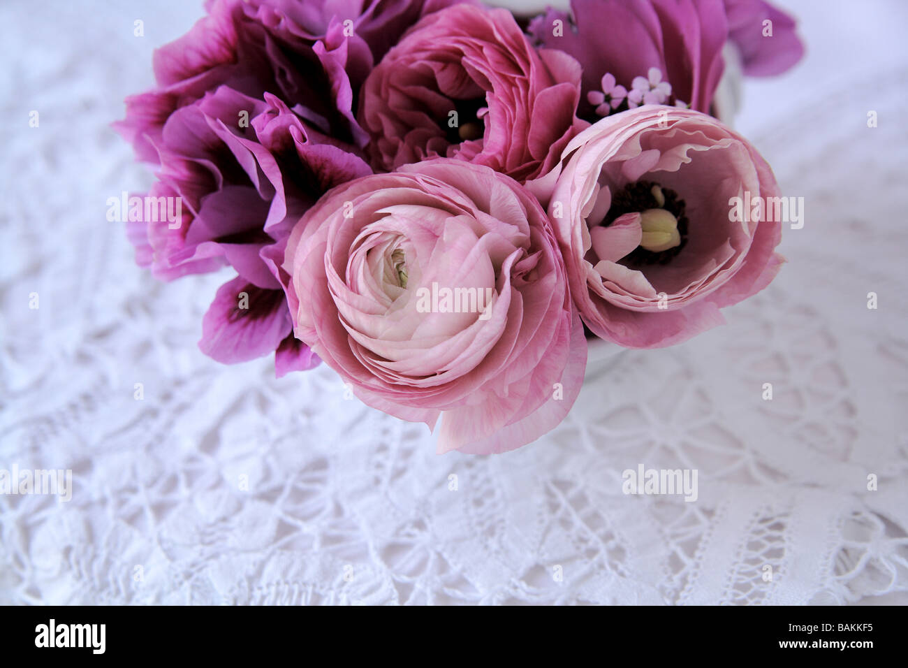 bouquet of pink ranunculus with pelargonium on lace Stock Photo - Alamy