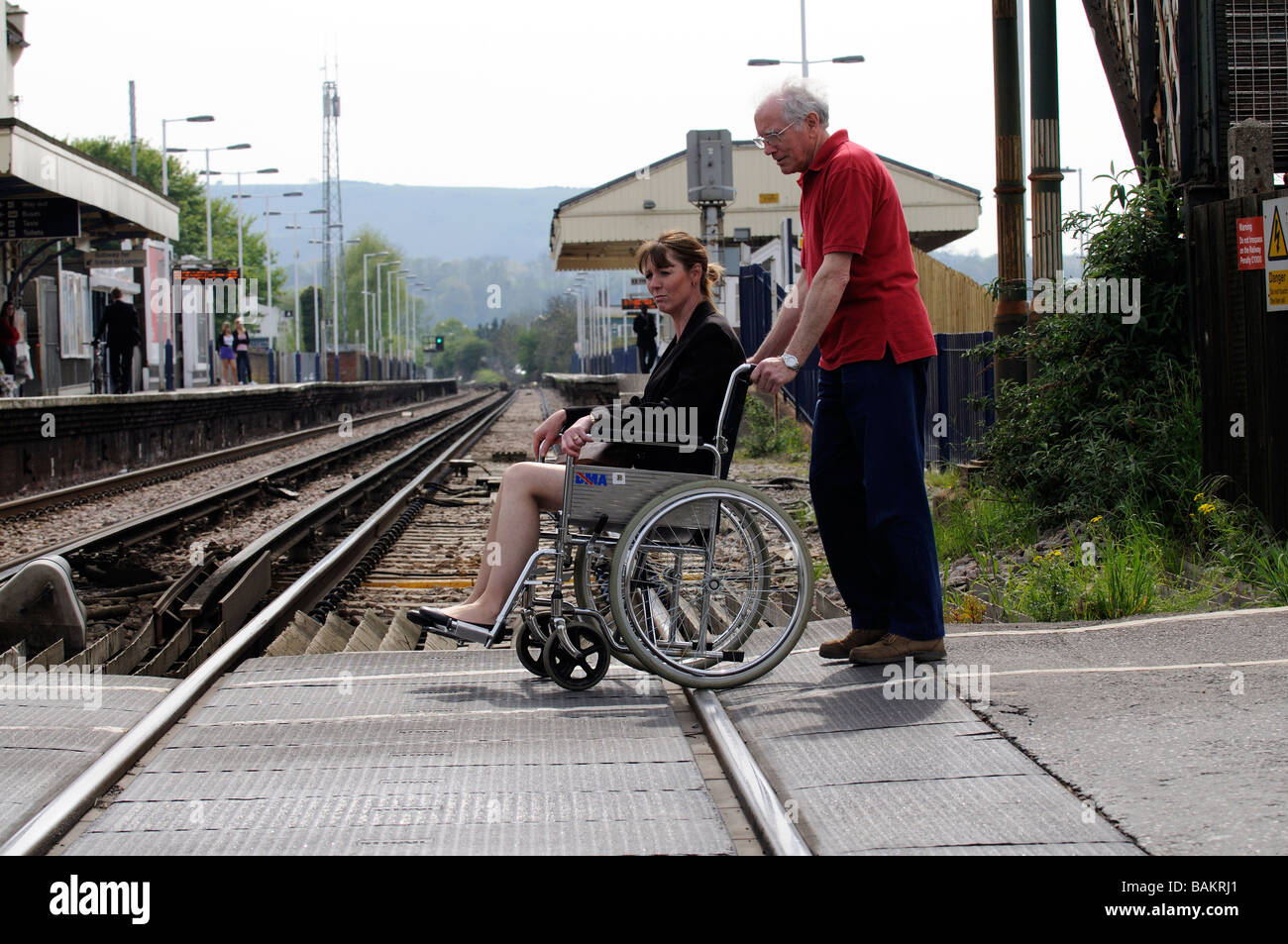 Female invalid wheelchair user and male carer using a railway level ...