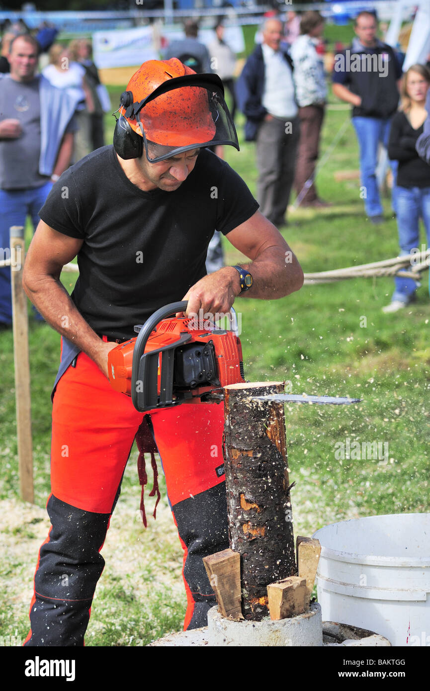 A logger using a chainsaw in a logging competition cutting against the ...
