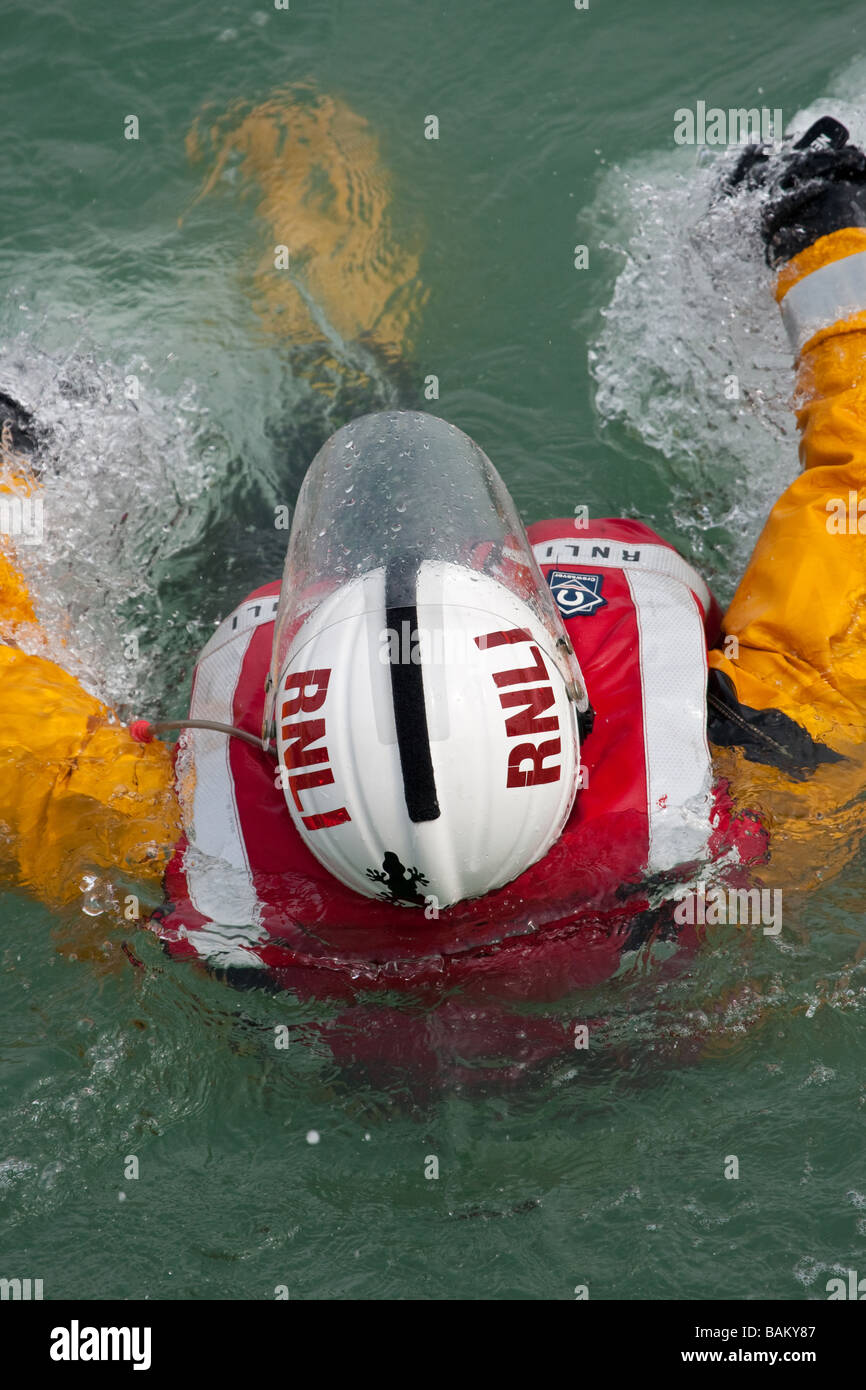 RNLI (Royal National Lifeboat Institution) crew member in the water ...