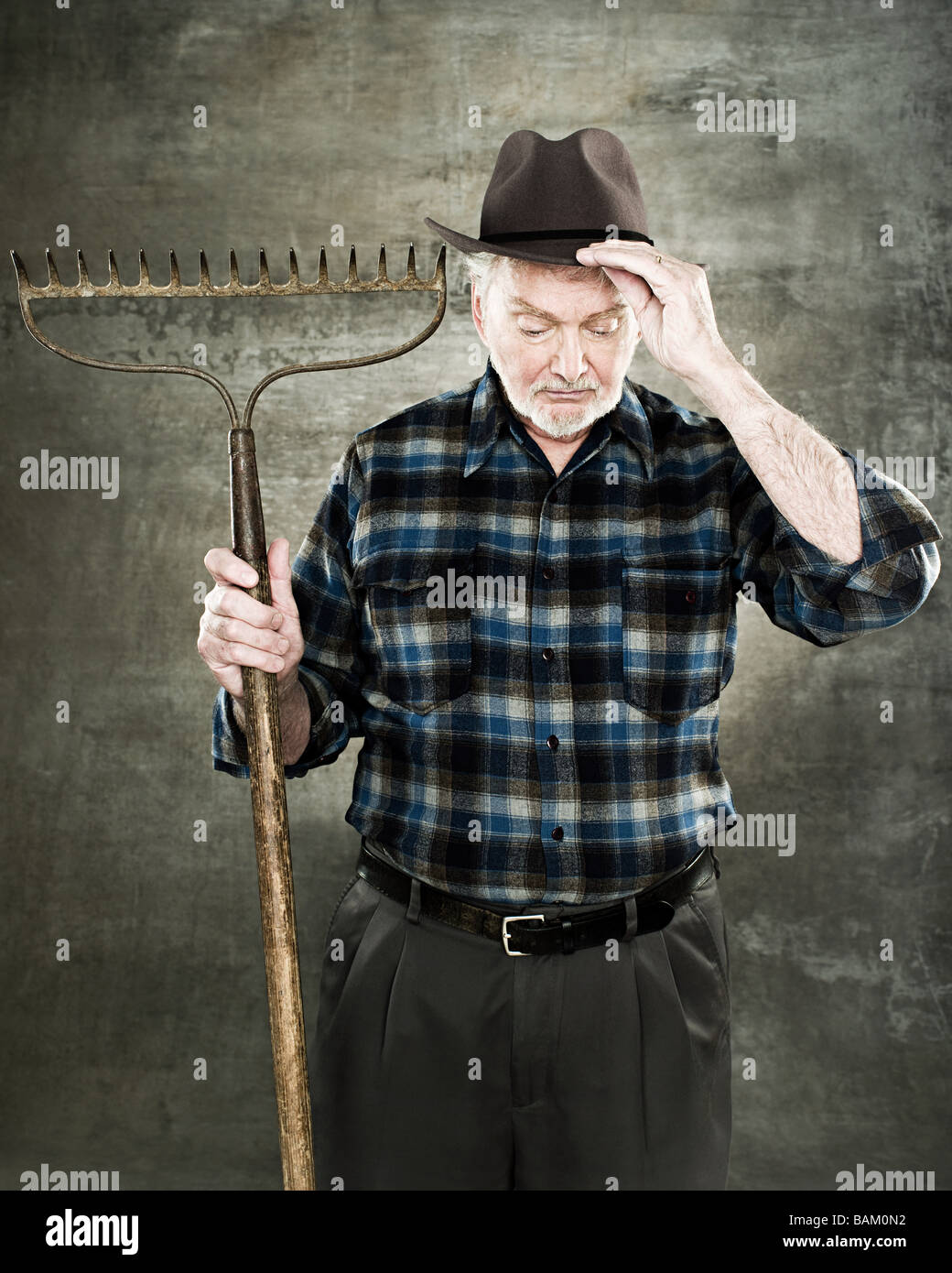 Portrait of a farmer holding a rake Stock Photo - Alamy