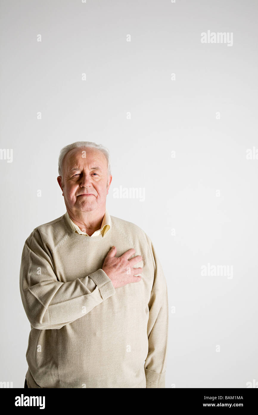Senior man with hand on heart Stock Photo - Alamy