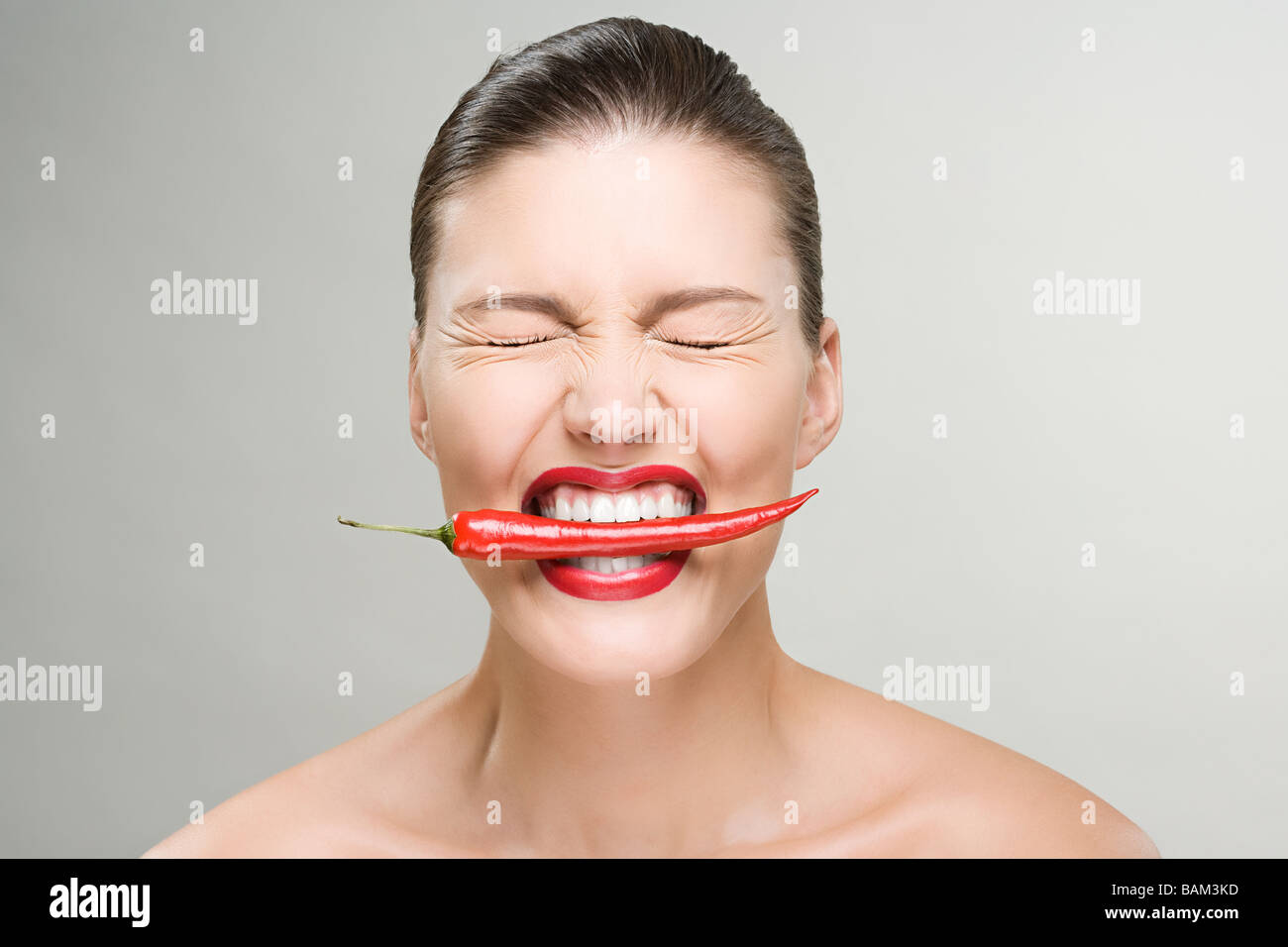 Woman with a red chili pepper in her mouth Stock Photo - Alamy