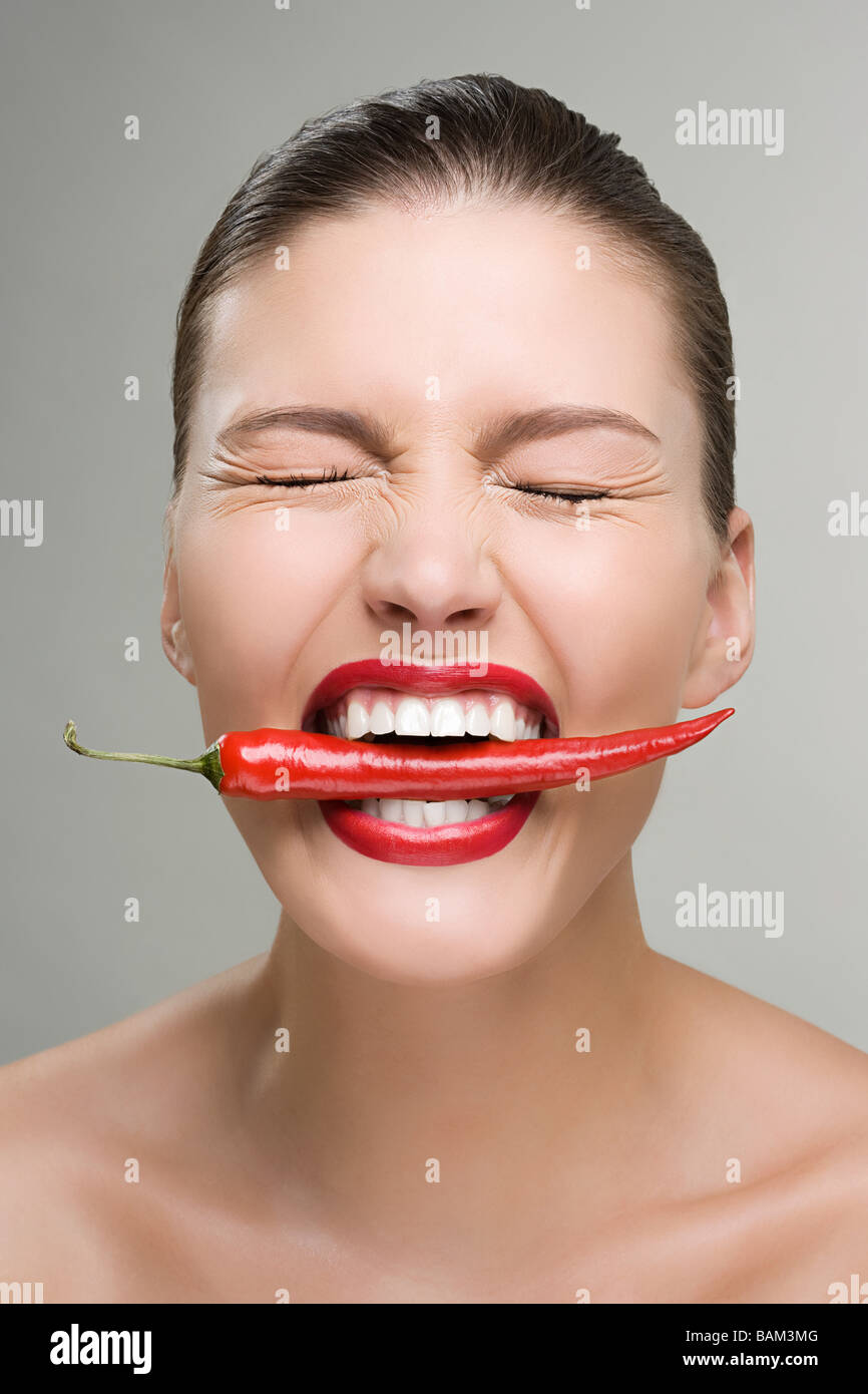 Woman biting a red chili pepper Stock Photo - Alamy