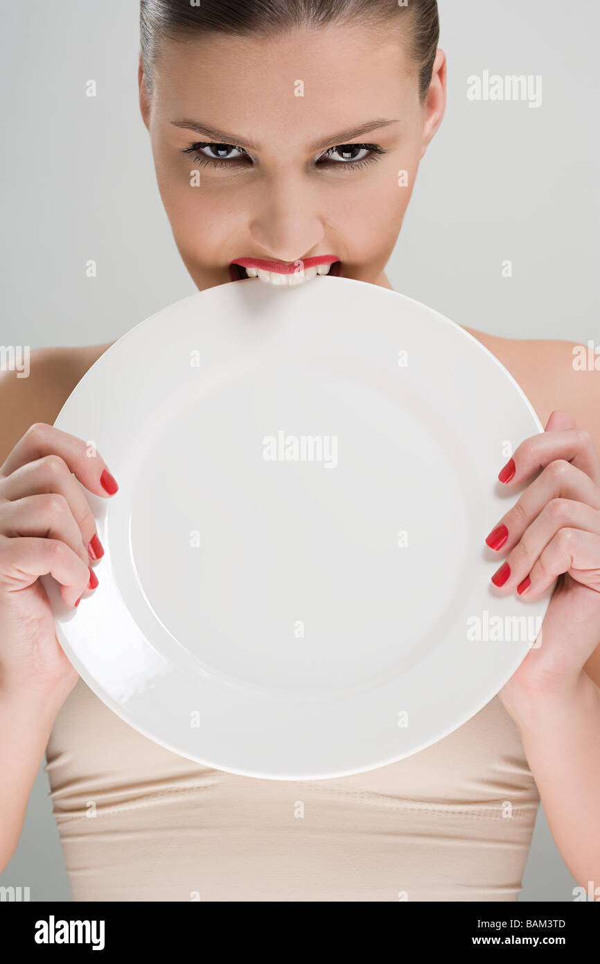 Woman biting a plate Stock Photo - Alamy