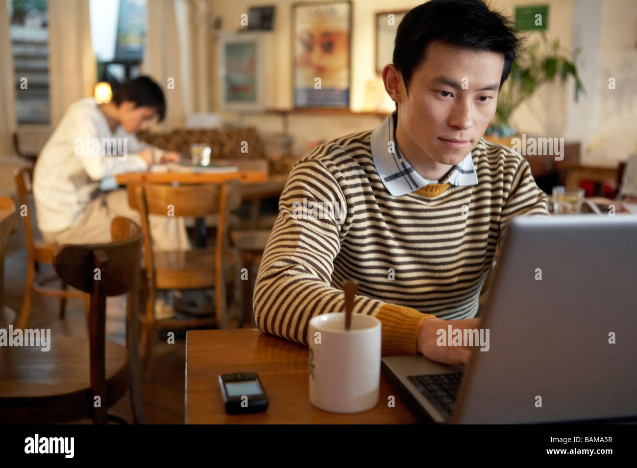 Young Man Sitting In Cafe On Laptop Computer Stock Photo - Alamy