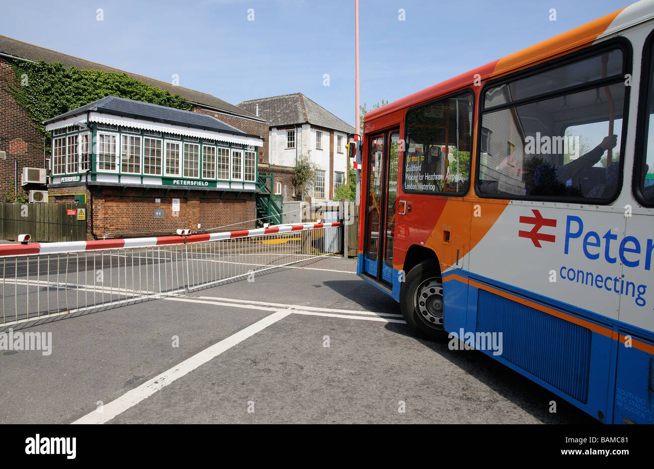 Single deck bus waits at Petersfield Station level crossing gates ...