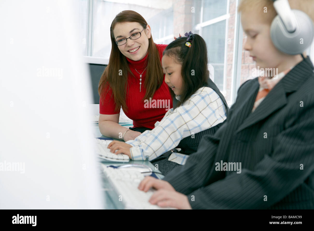 Teacher Watching Children Using Computers Stock Photo - Alamy