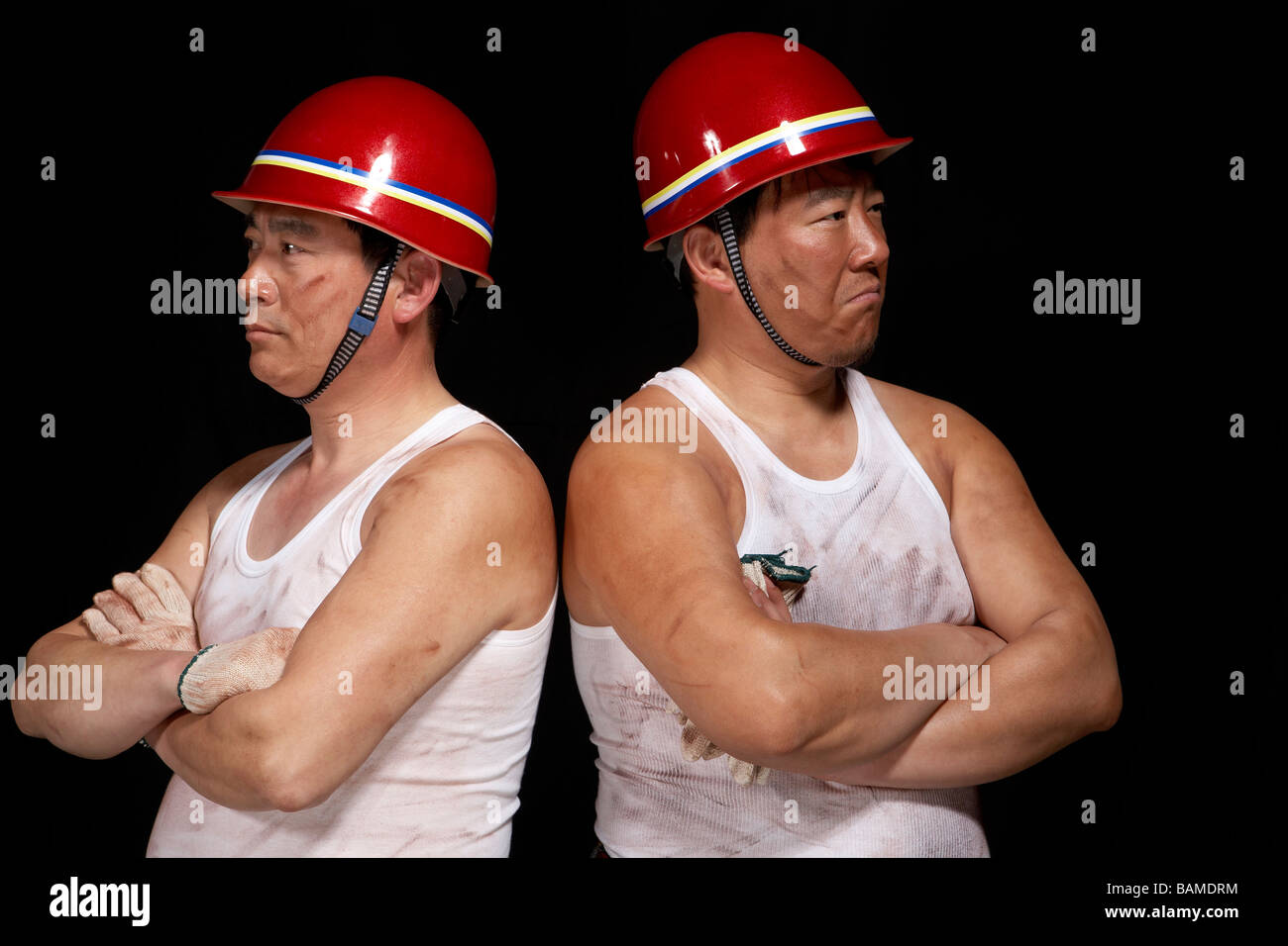 Men Standing Back To Back Wearing Hard Hats With Arms Folded Stock ...