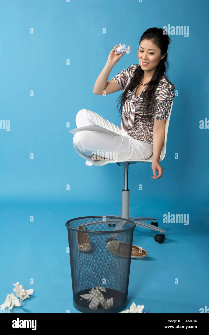 Woman Sitting On Chair, Throwing Paper Into Bin Stock Photo - Alamy
