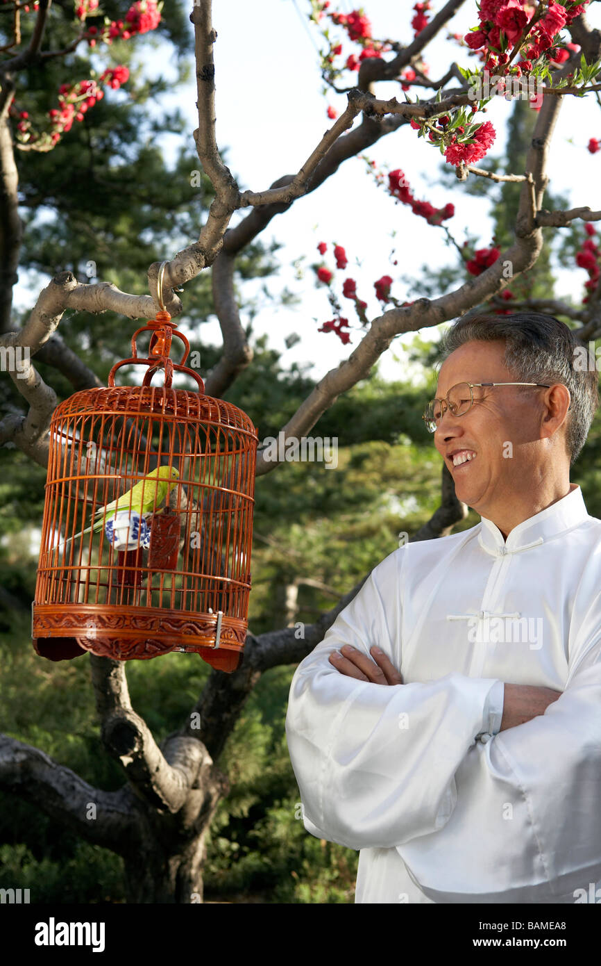 Chinese Man Looking At Bird In Cage Stock Photo - Alamy