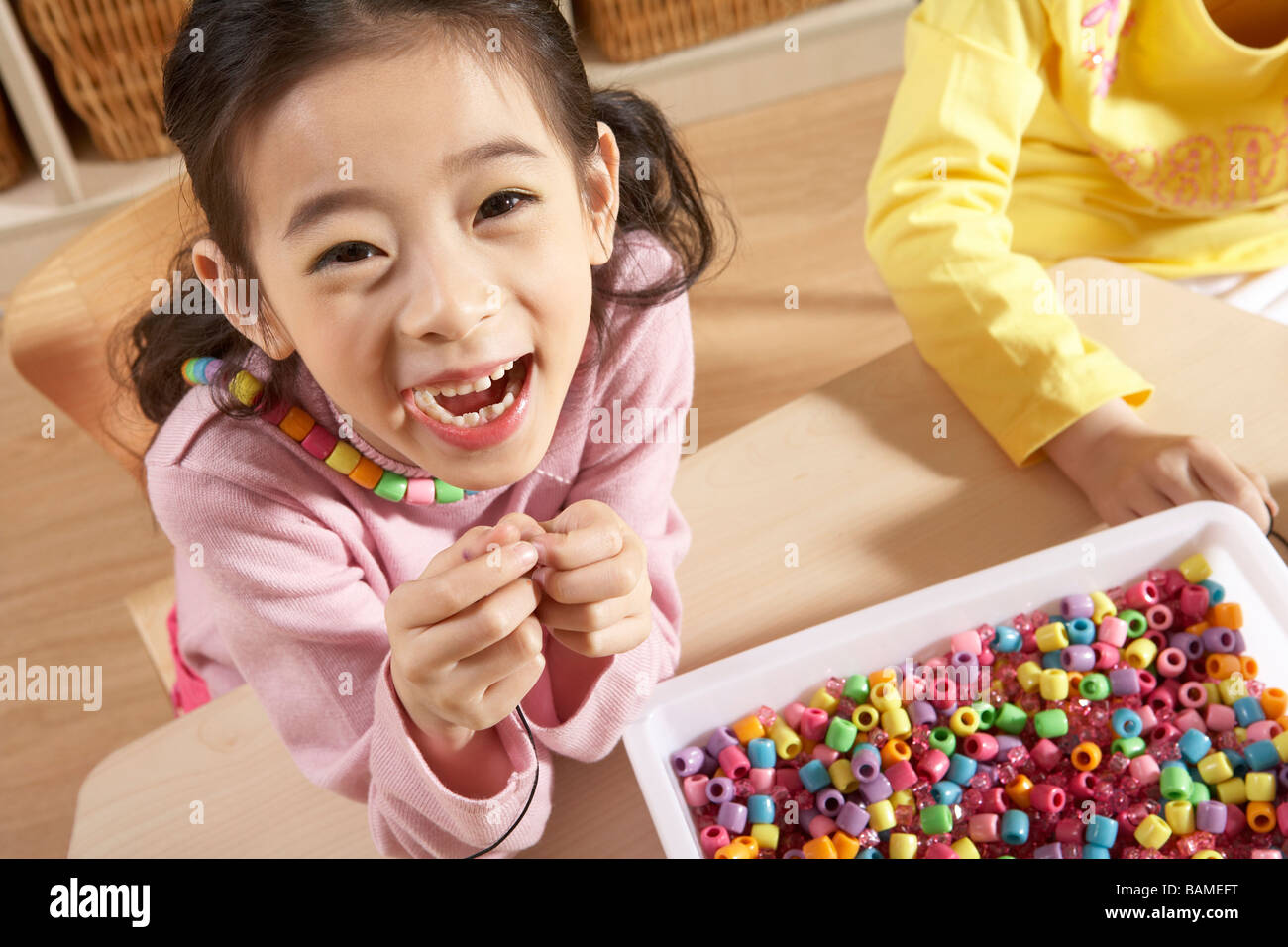 Girl In Classroom Laughing And Playing With Beads Stock Photo - Alamy