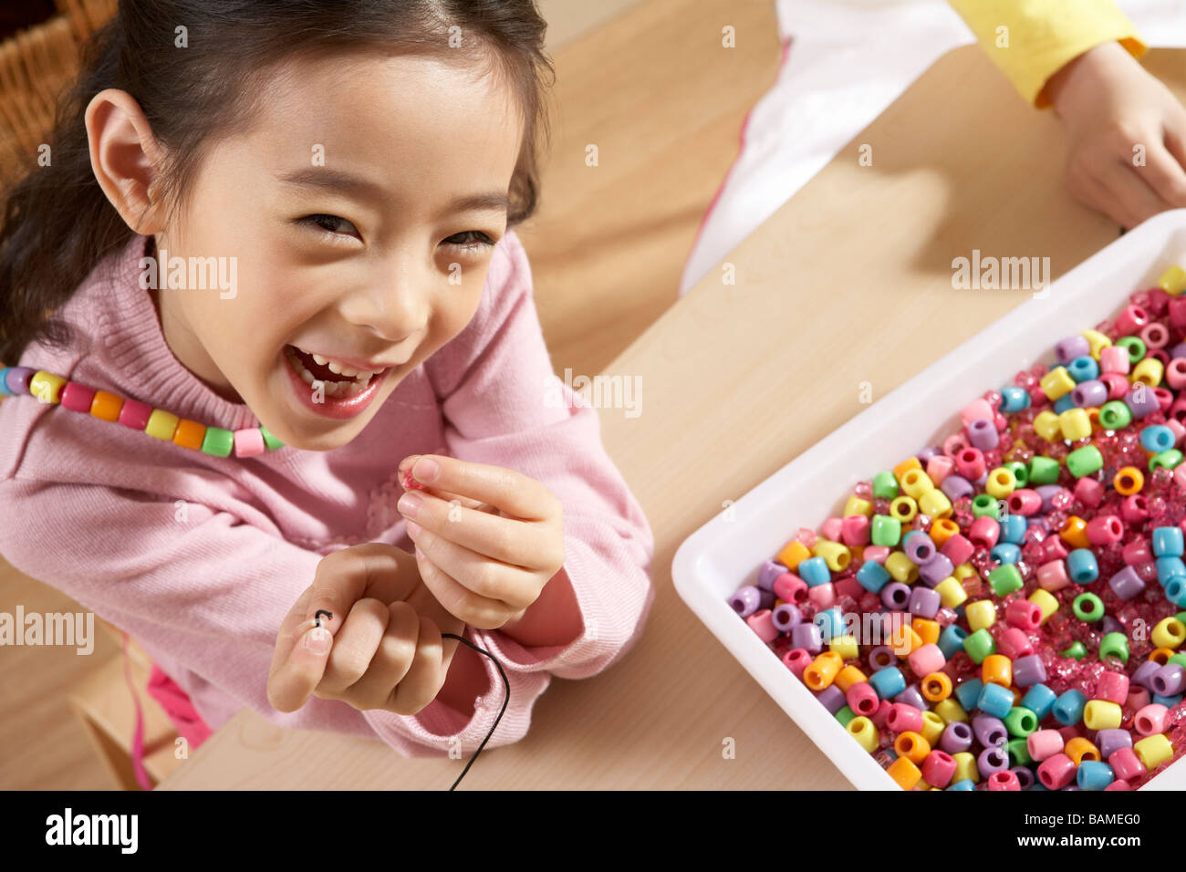 Girl In Classroom Laughing And Playing With Beads Stock Photo - Alamy