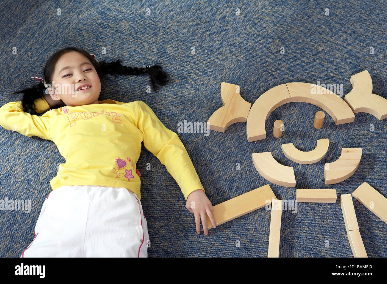Girl Lying Down Next To Wooden Shapes Stock Photo - Alamy