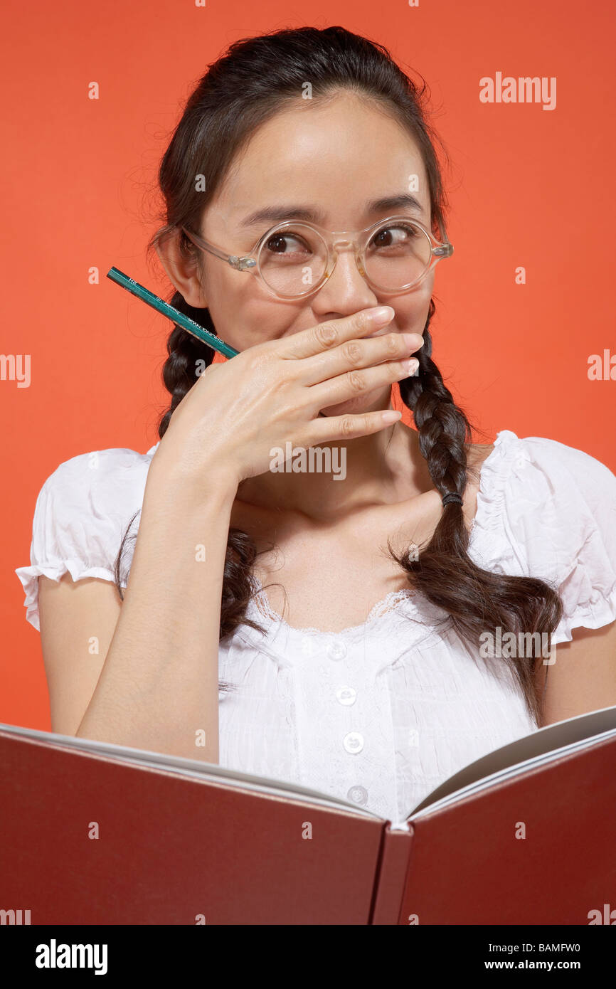 Young Girl Holding A Book And Pencil Laughing Stock Photo - Alamy